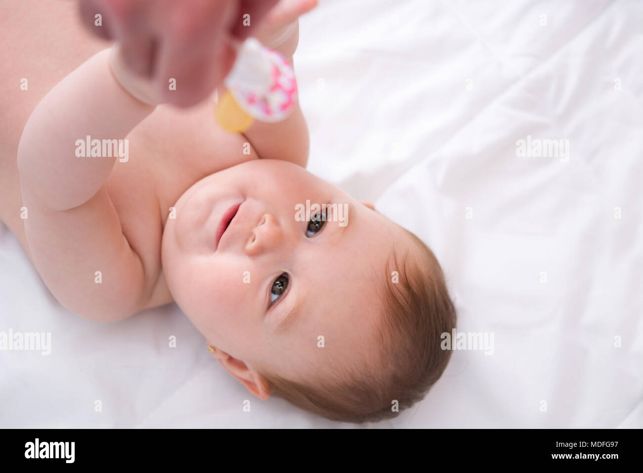 Adorable little baby girl playing with a pacifier on white bed Stock ...