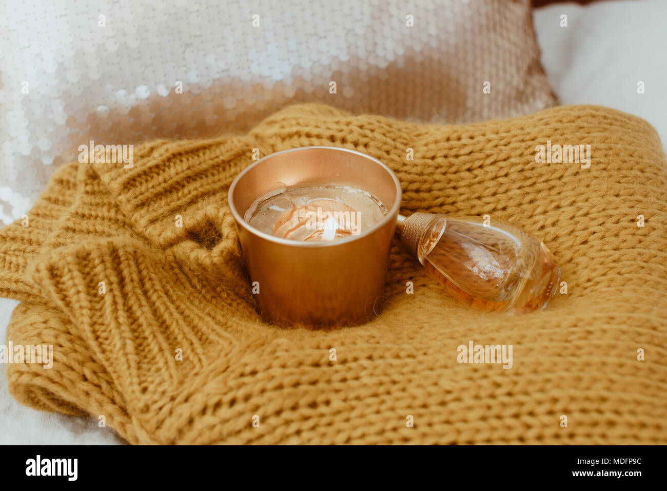 Candle and perfume on a knitted sweater Stock Photo - Alamy
