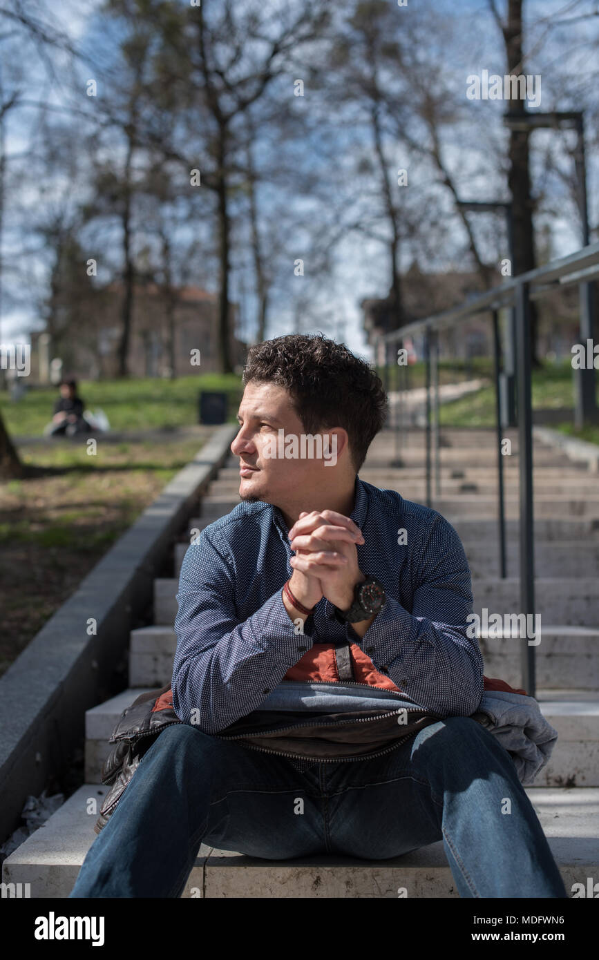 Man sitting on steps in public park Stock Photo - Alamy