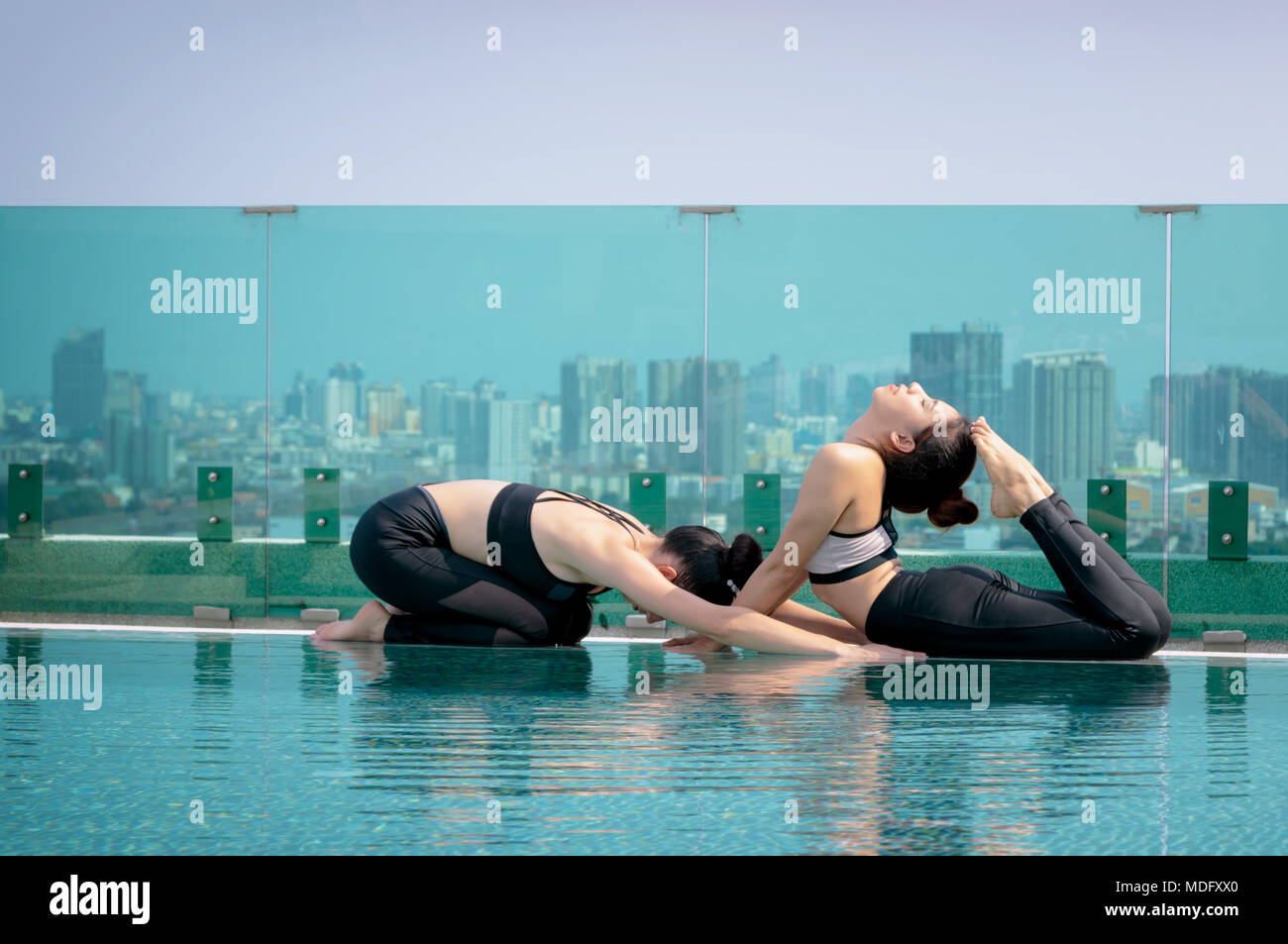 Two young women doing yoga pose at the swimming pool Stock Photo - Alamy