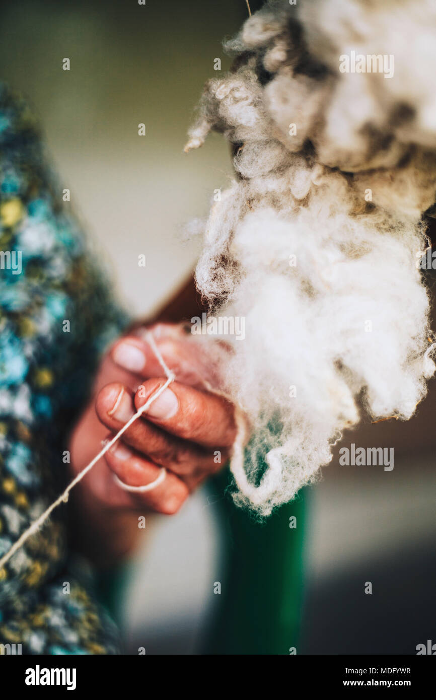 Closeup of fingers of a old woman is making yarn for knitting from ...