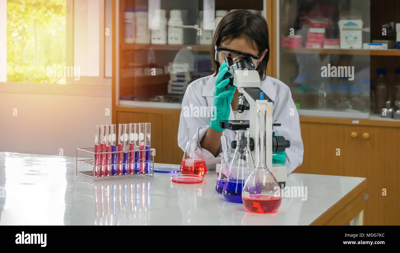 asian little scientist looking through a microscope in a laboratory ...