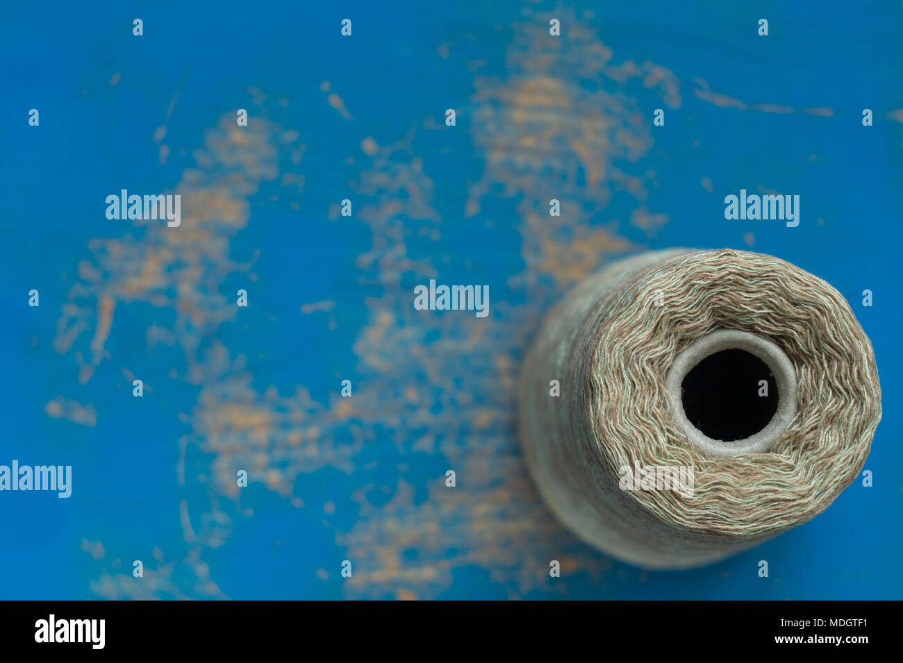 Coil with gray threads on a blue wooden surface Stock Photo - Alamy