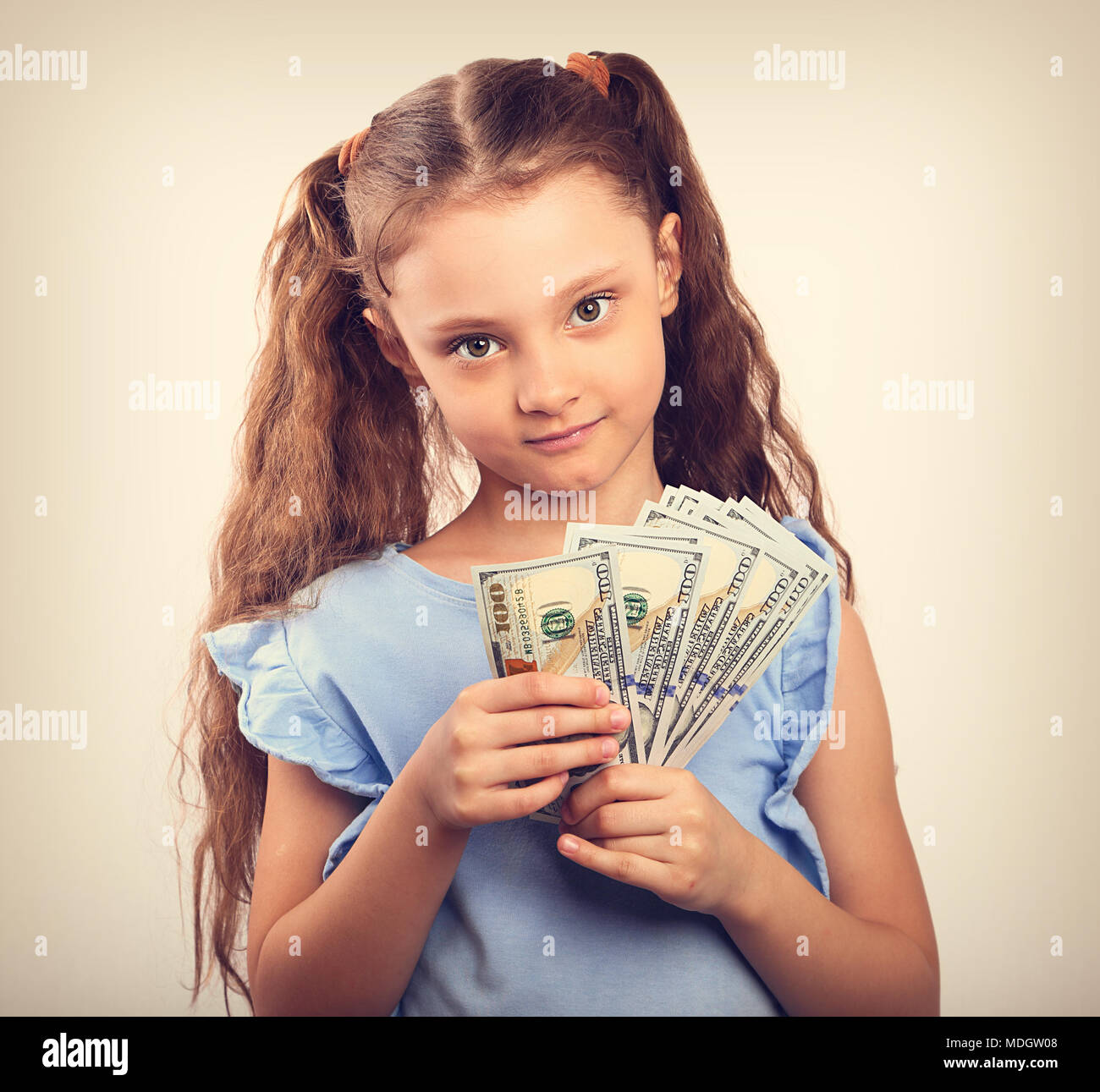 Happy smiling rich kid girl holding money two hands. Vintage toned ...