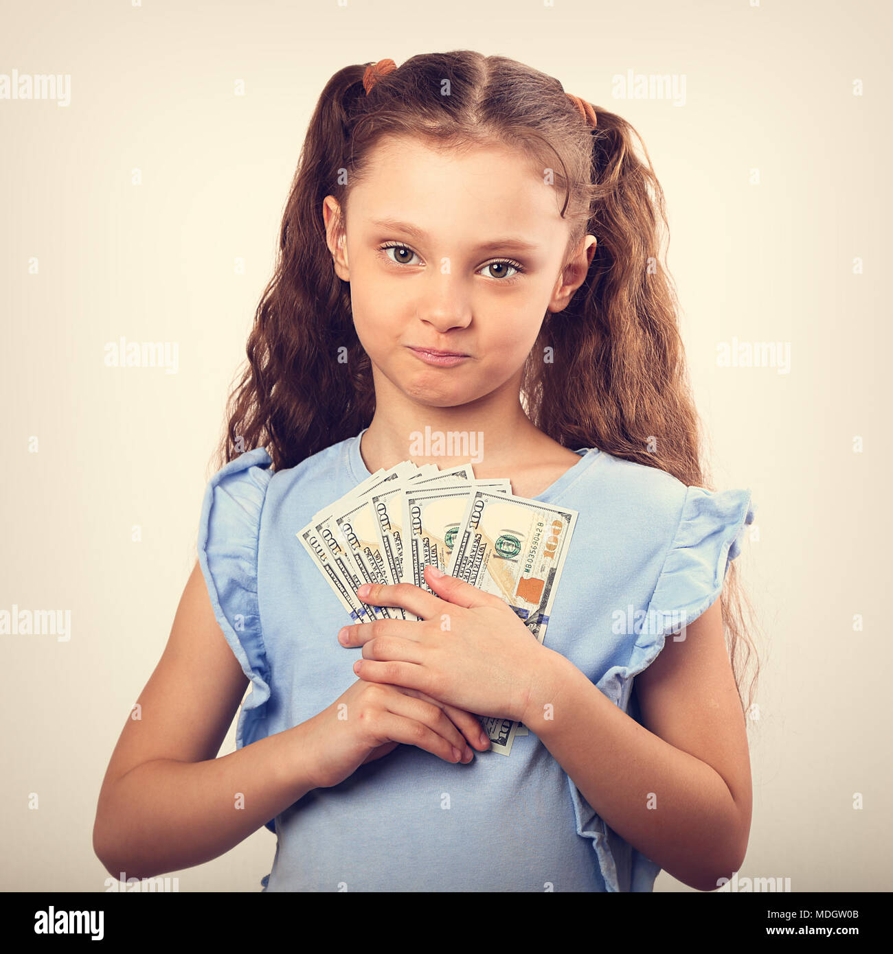 Happy smiling rich kid girl holding money and presseing to the chest ...