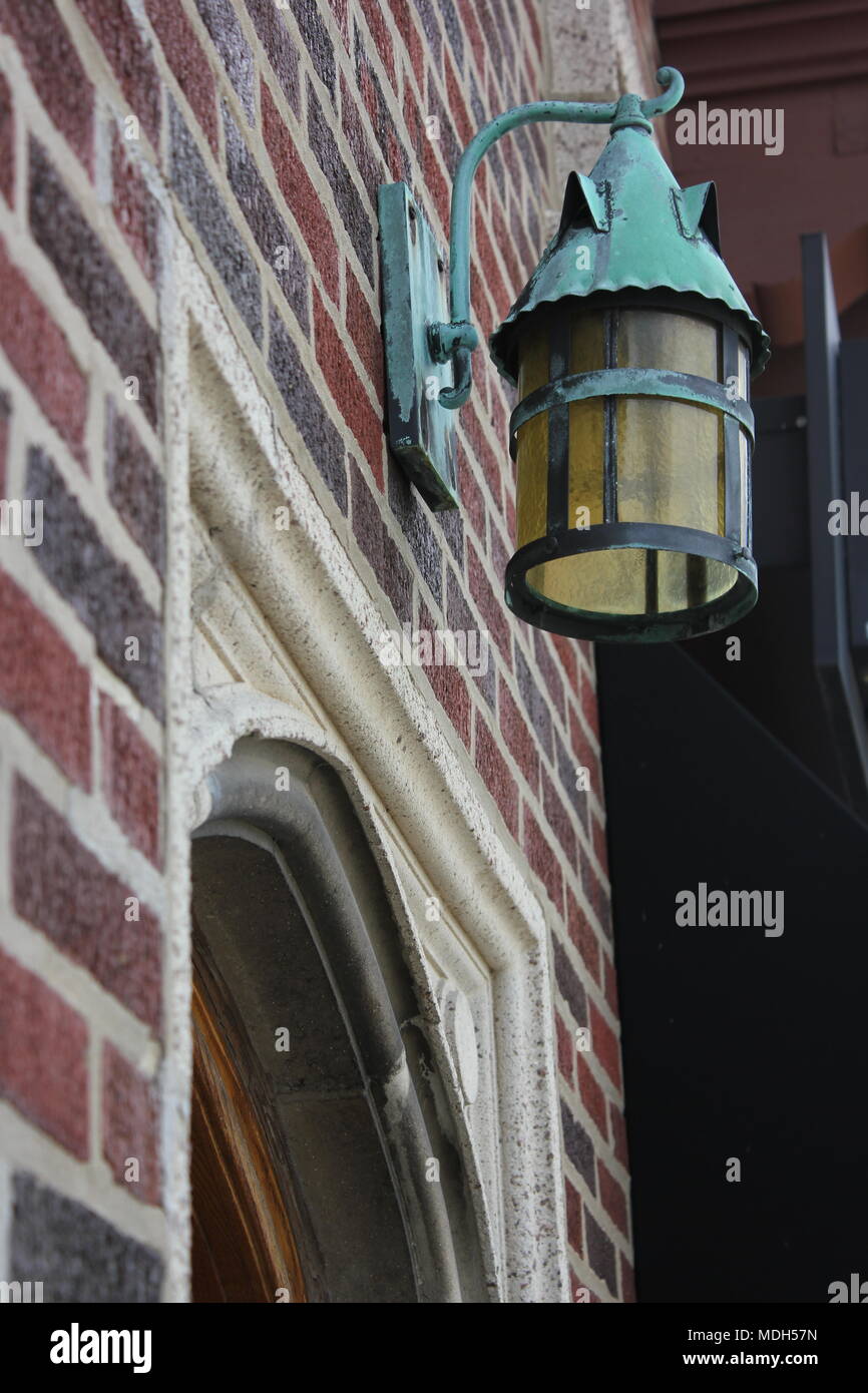 Weathered copper coach light hanging above a doorway on a red brick ...