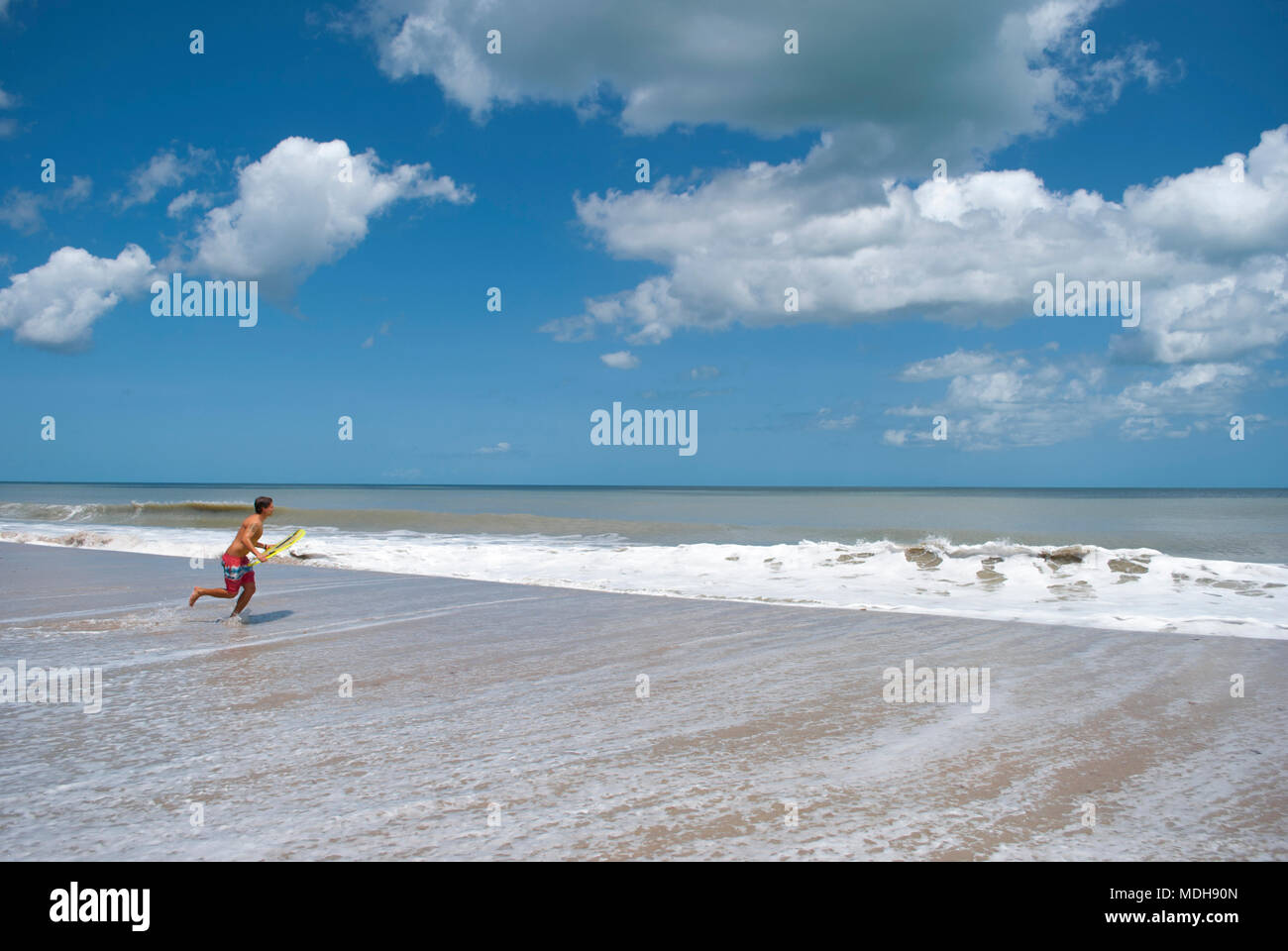 Surfer rides ocean wave. Young man running by ocean shore with surfing ...