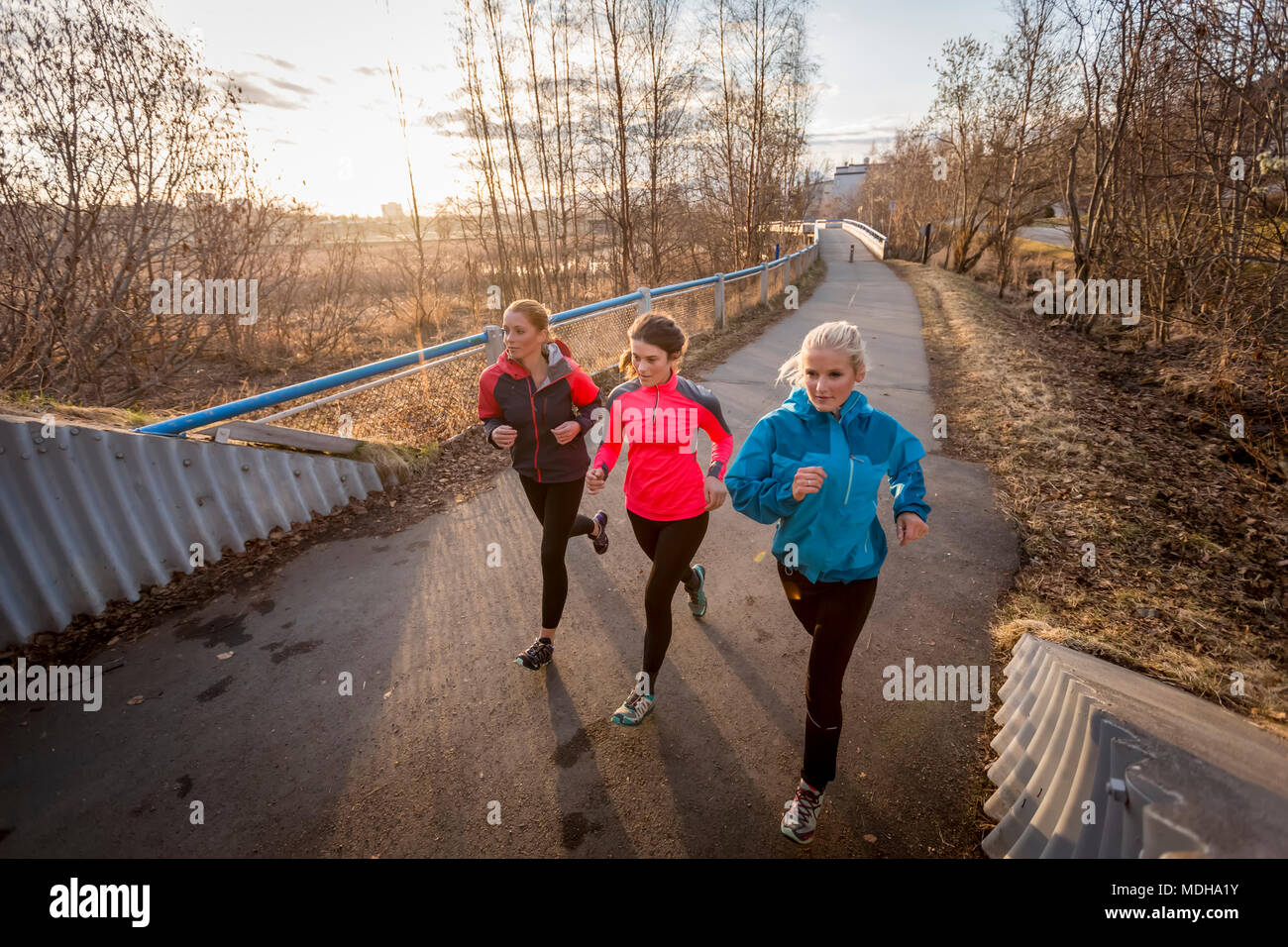 Three young women running on a trail at sunrise; Anchorage, Alaska ...