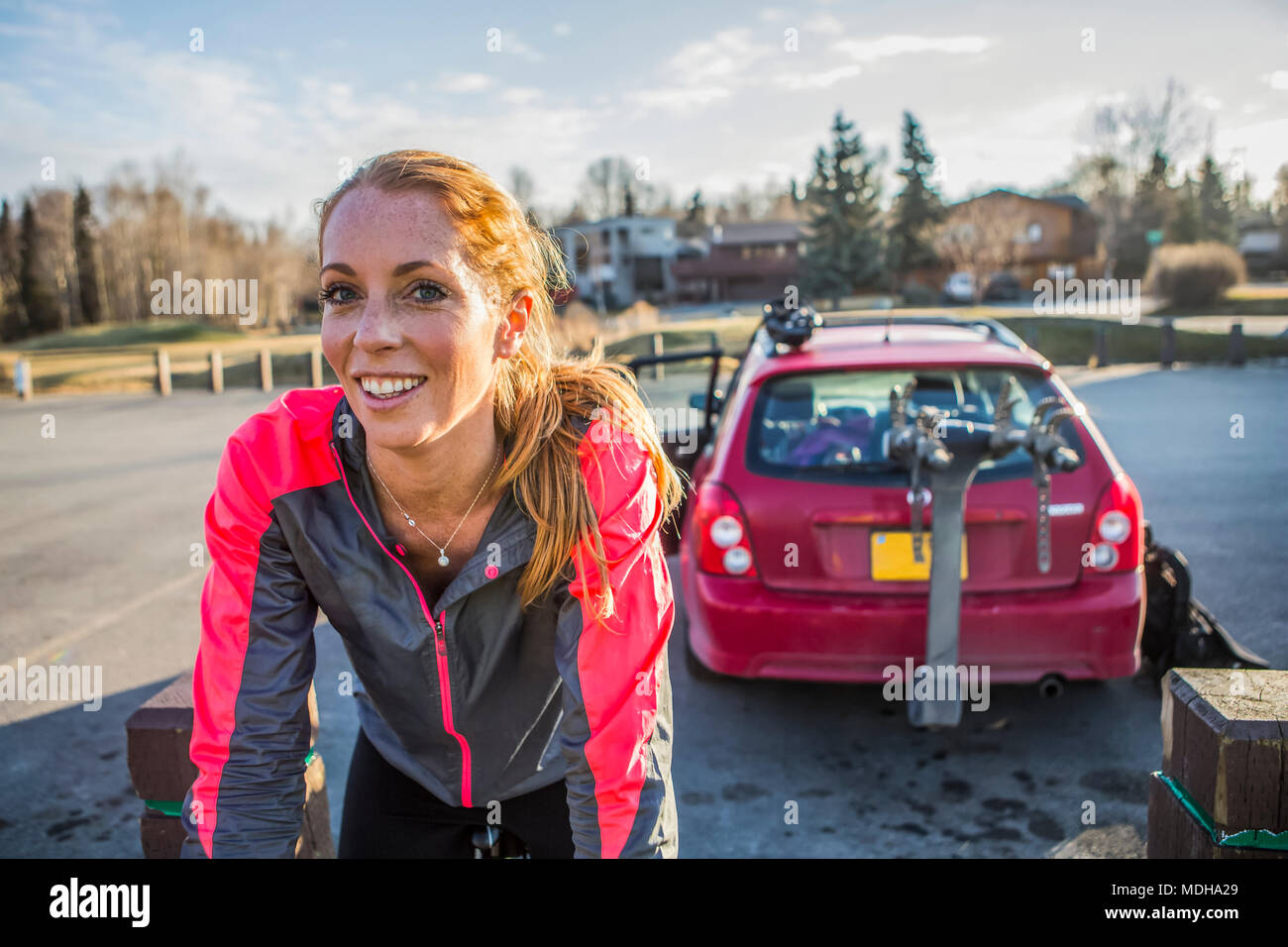 A woman with red hair and freckles sits on a bike with her car and bike ...