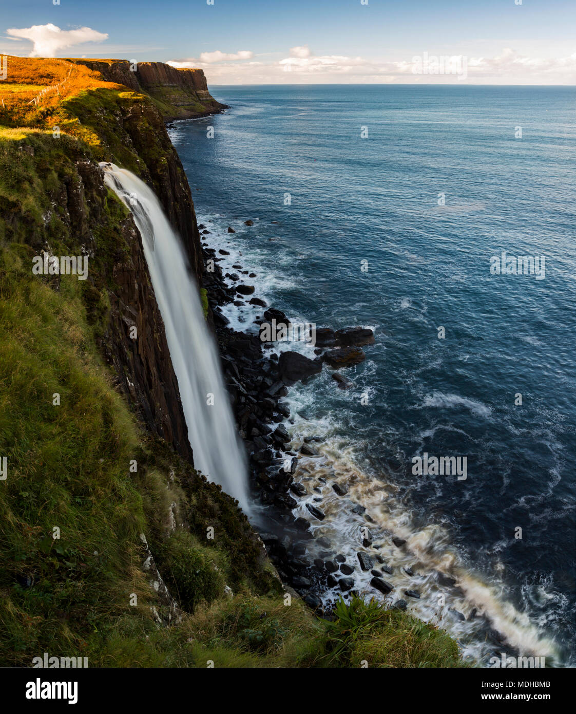 A waterfall flowing over a cliff along the coastline; Isle of Skye ...