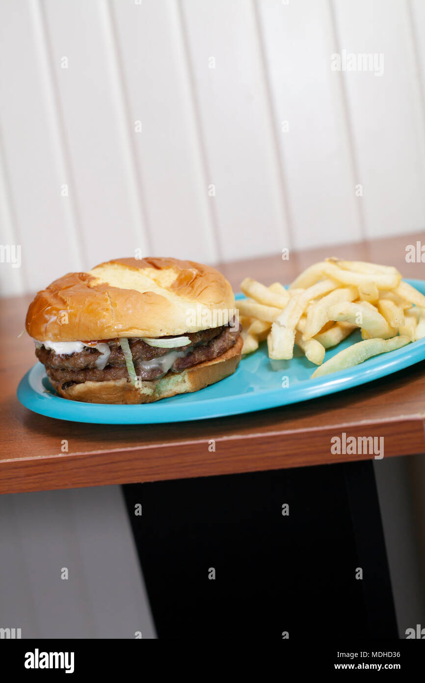 Double cheeseburger on a sweet bun with a side of fries Stock Photo - Alamy