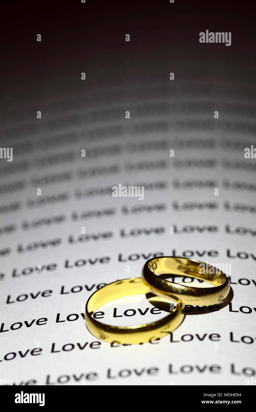 Two gold wedding rings on a page with the word love repeated Stock ...