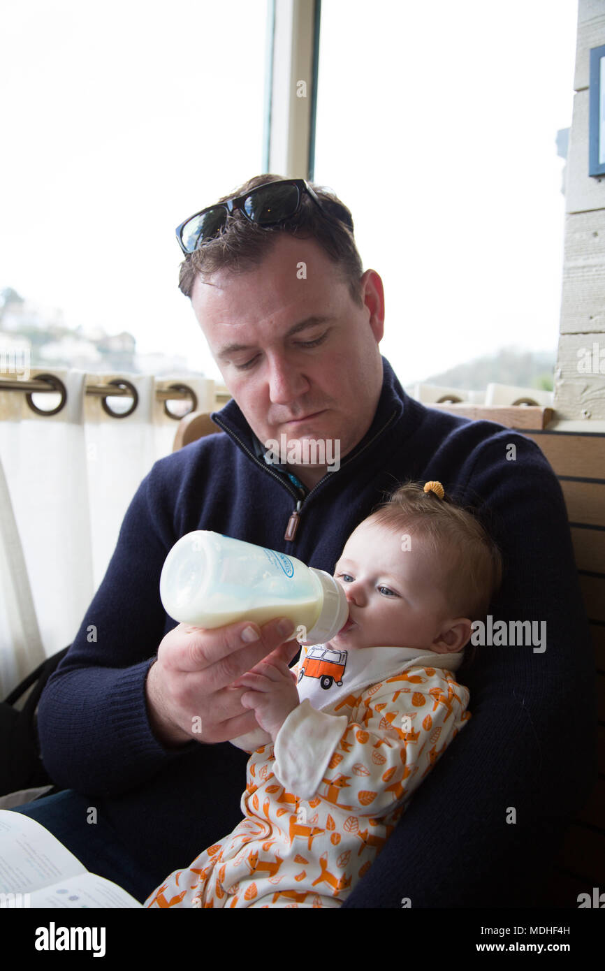 Dad feeding baby bottle in restaurant Stock Photo - Alamy