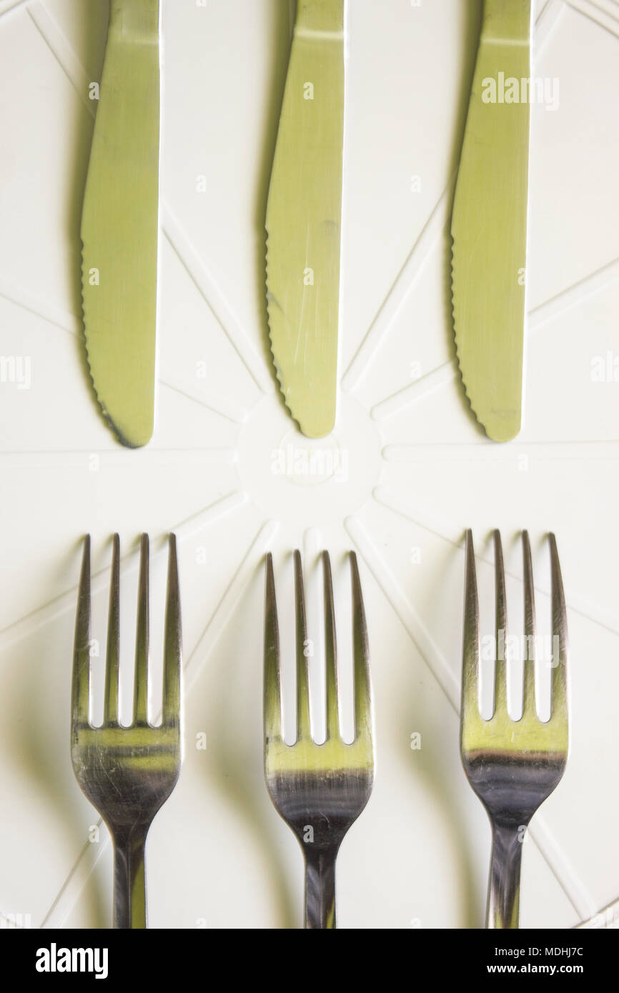 three fork and knives pointing in the same direction on white ...