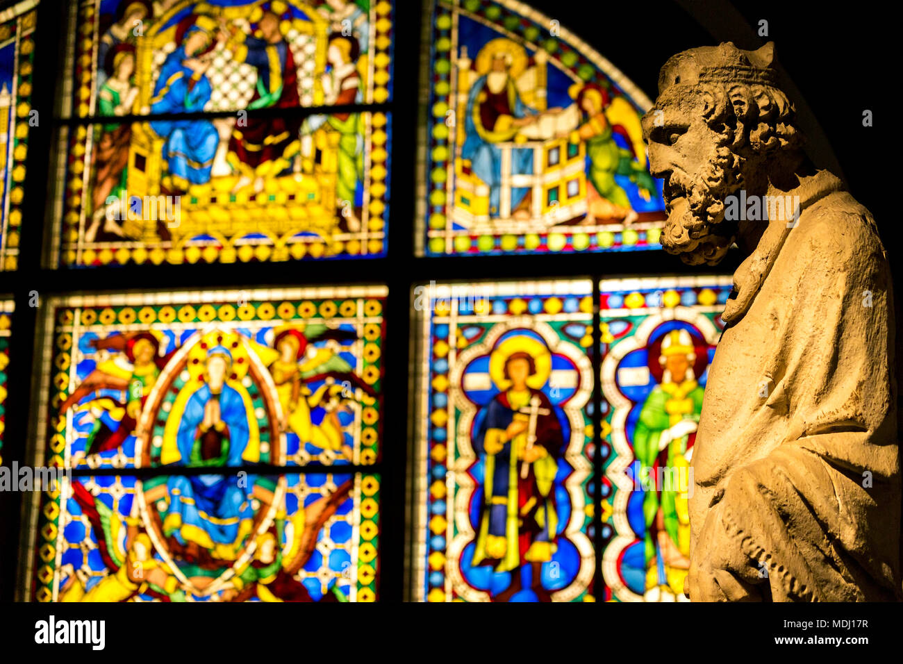 Stone statue with stain glass window in background in a church; Siena ...