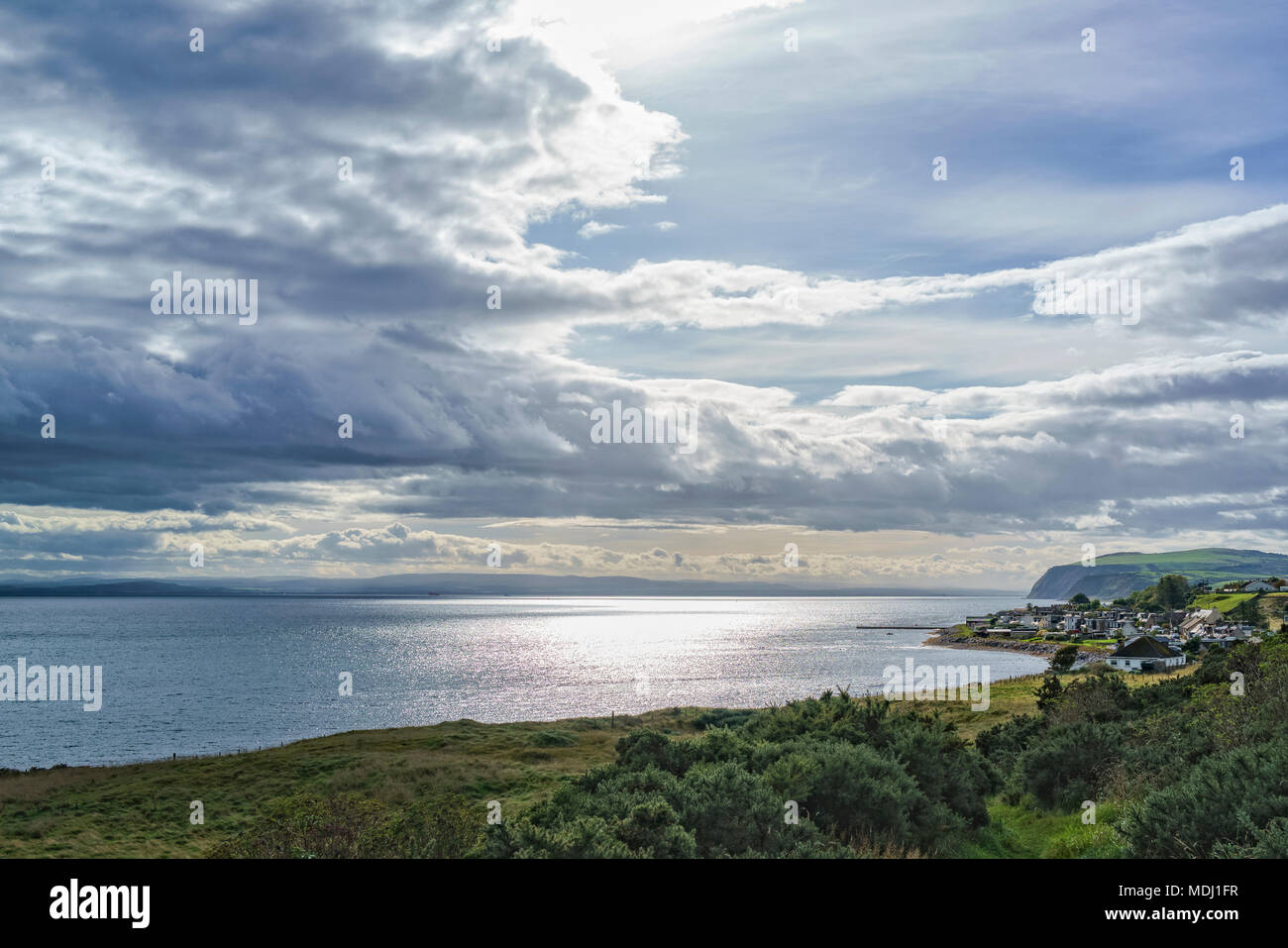Sunlight illuminates clouds and reflects on the tranquil ocean along ...
