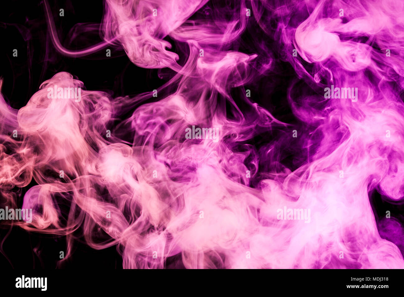 Thick colorful pink and red smoke on a black isolated background ...