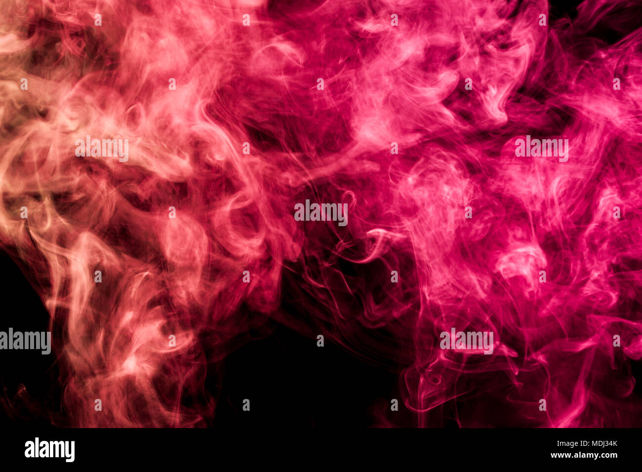 Thick colorful pink and red smoke on a black isolated background ...