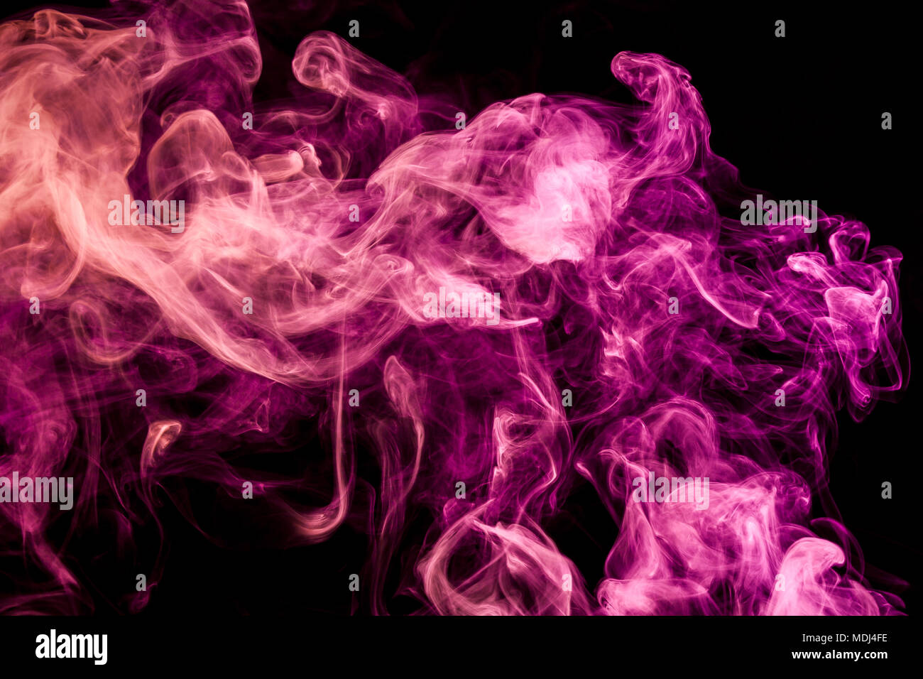 Dense multicolored pink and red smoke on a black isolated background ...
