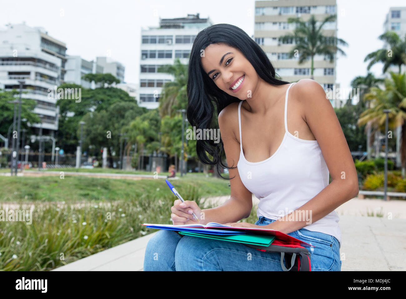 Laughing native latin american female student learning outdoors on ...