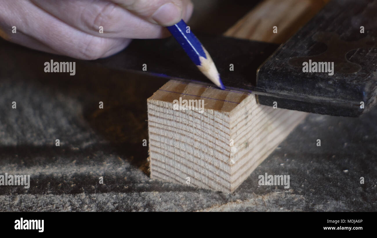 close up very close hands of a carpenter marking the cutting line with ...