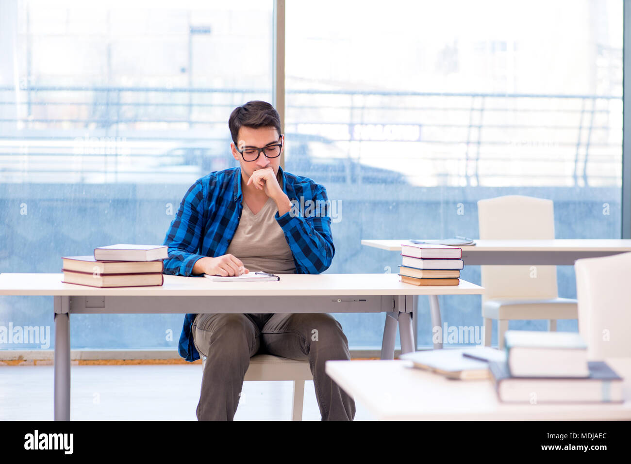Student studying in the empty library with book preparing for exam ...