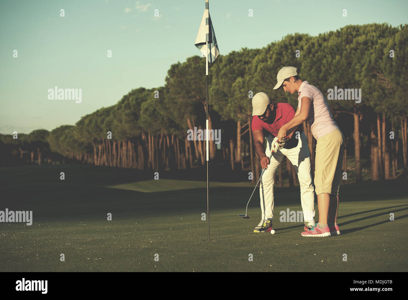 male golf instructor teaching female golf player, personal trainer ...