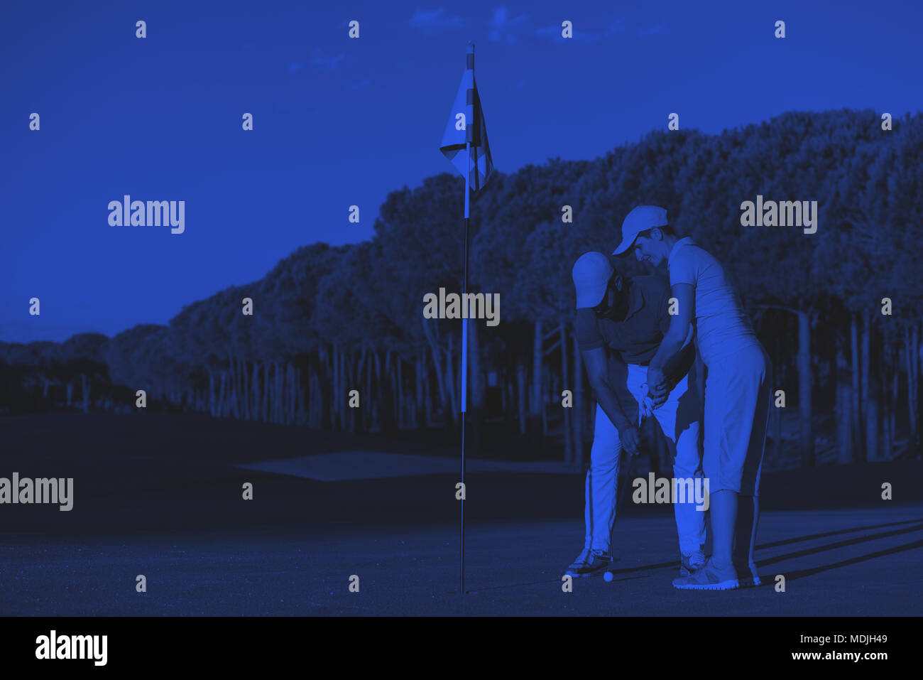 male golf instructor teaching female golf player, personal trainer ...