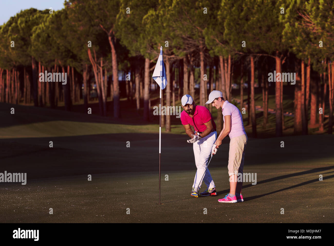 male golf instructor teaching female golf player, personal trainer ...