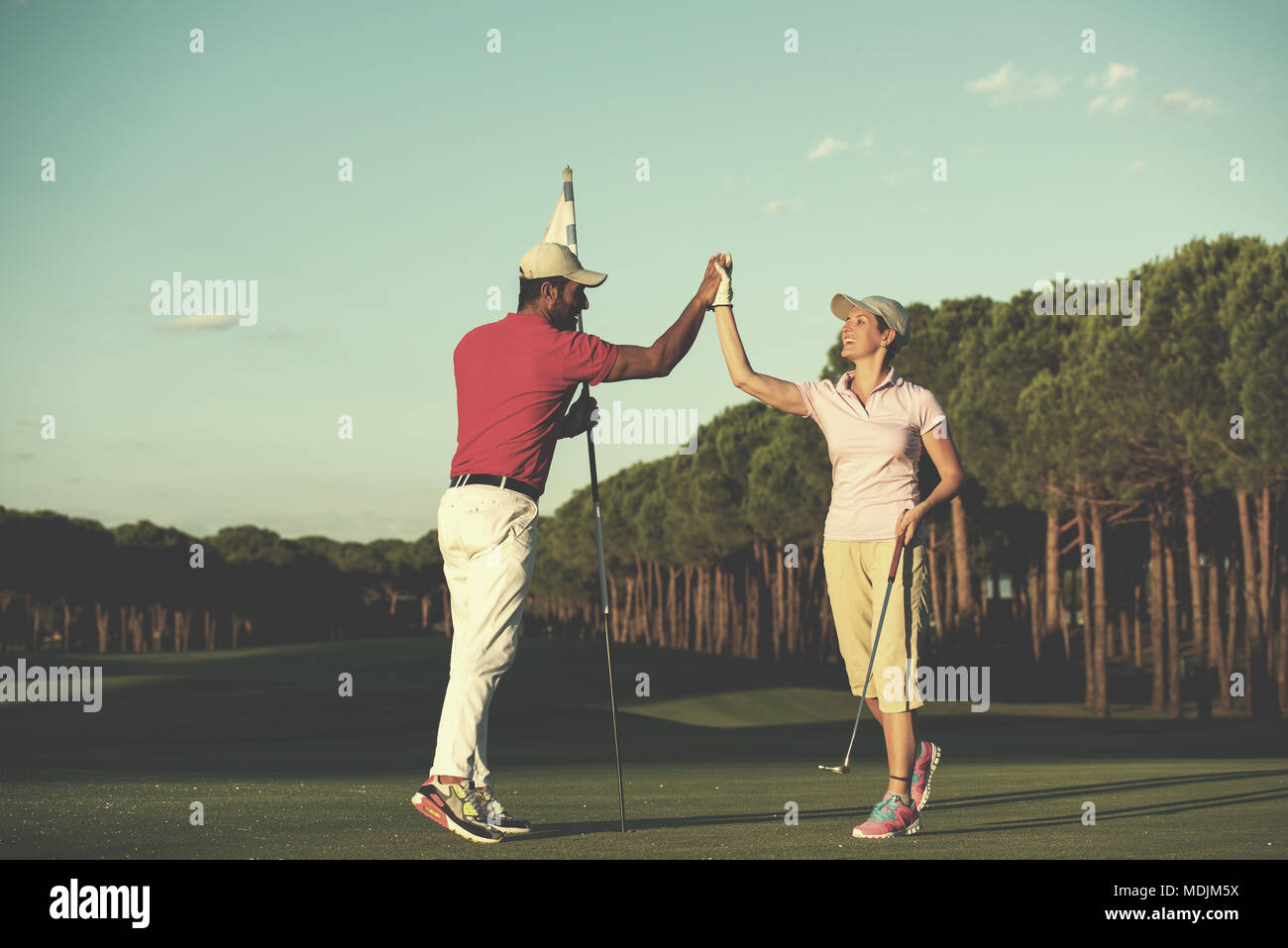 male golf instructor teaching female golf player, personal trainer ...