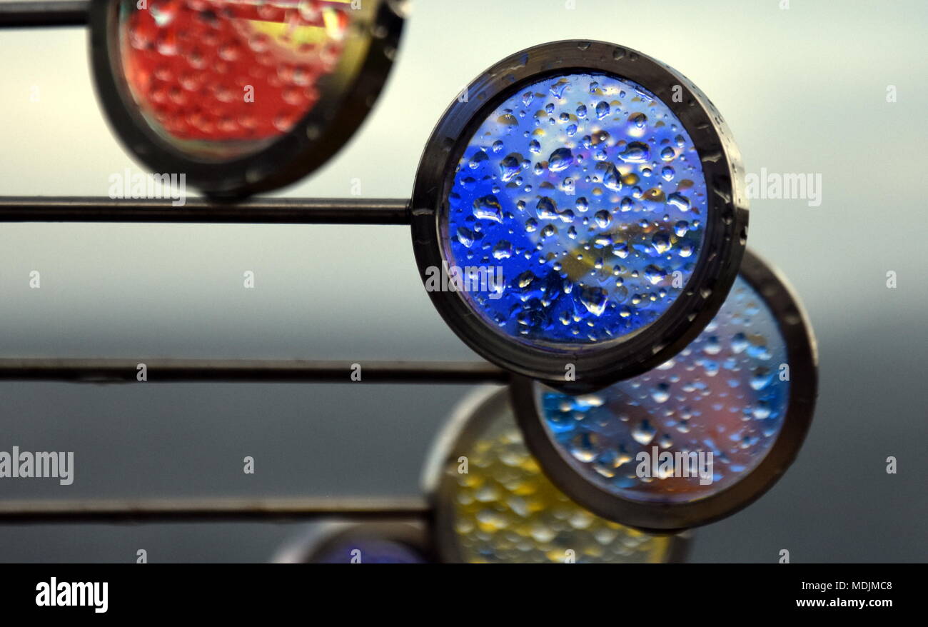 Wet, red and blue, round shaped glass outdoor decoration on a rainy day ...