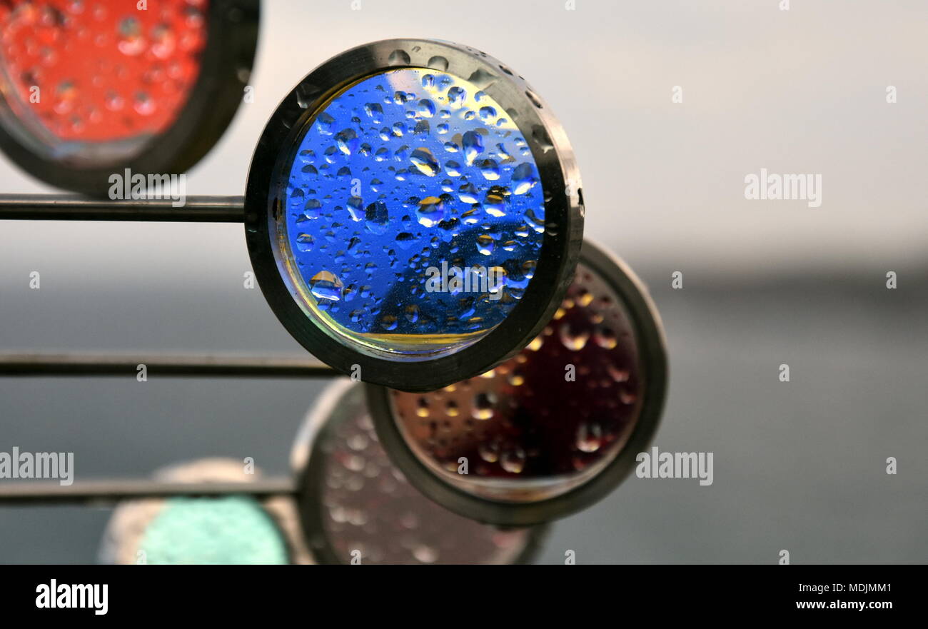 Wet, red and blue, round shaped glass outdoor decoration on a rainy day ...