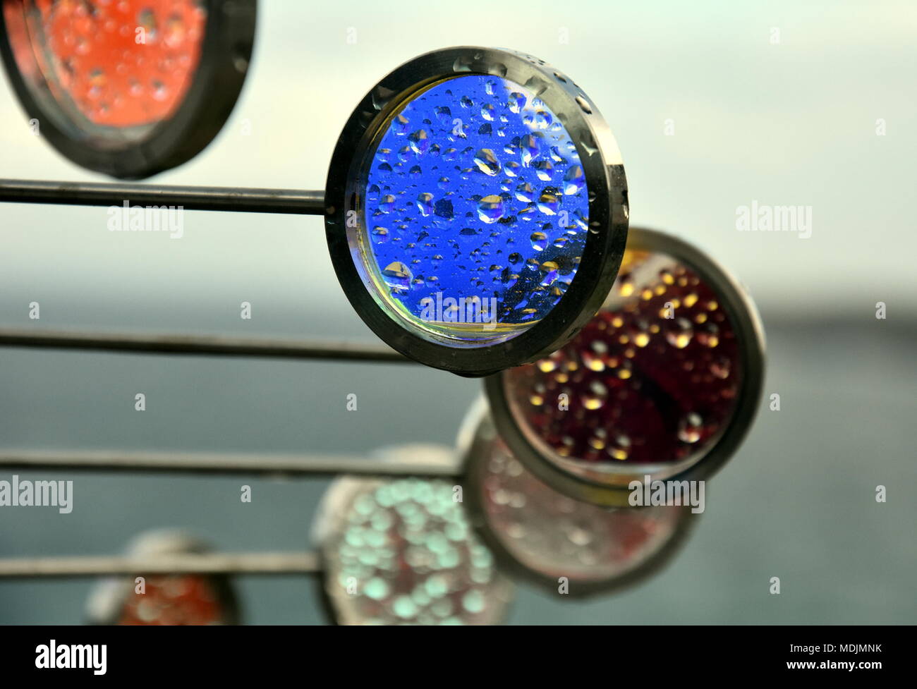 Wet, red and blue, round shaped glass outdoor decoration on a rainy day ...