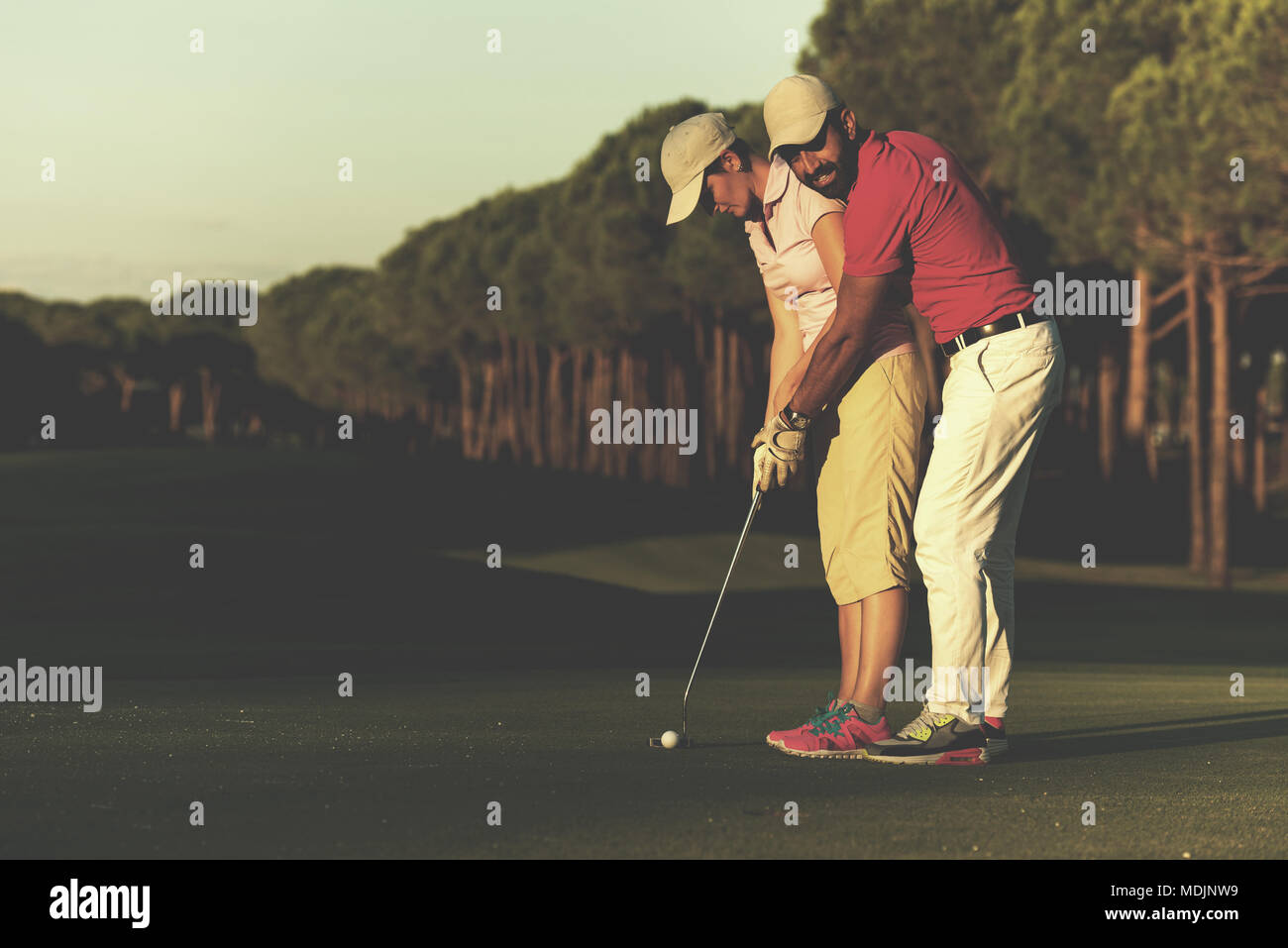 male golf instructor teaching female golf player, personal trainer ...