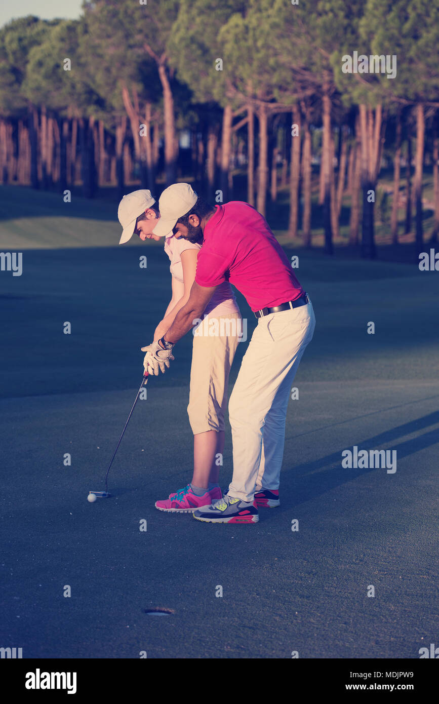 male golf instructor teaching female golf player, personal trainer ...
