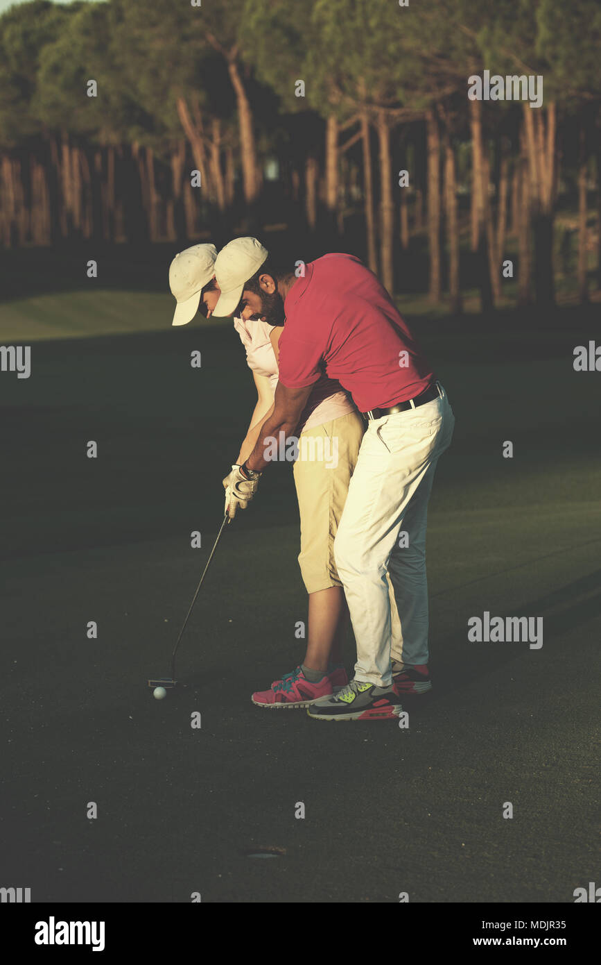 male golf instructor teaching female golf player, personal trainer ...