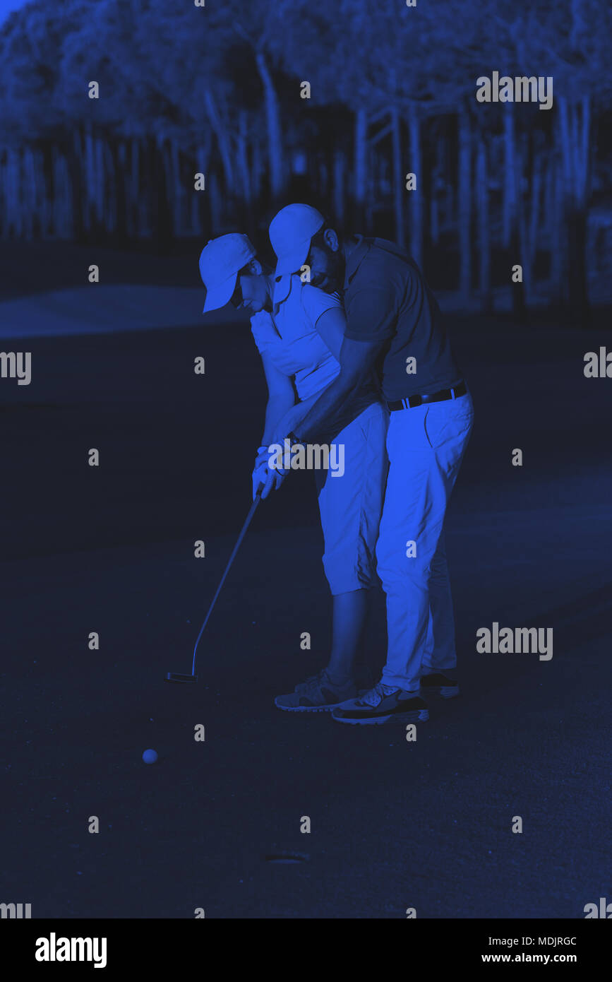 male golf instructor teaching female golf player, personal trainer ...