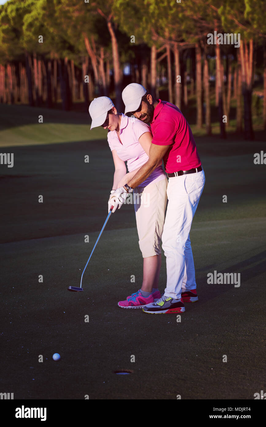 male golf instructor teaching female golf player, personal trainer ...
