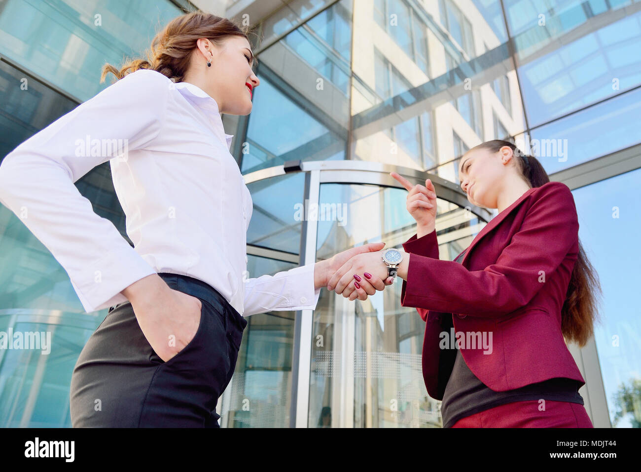 Handshake of two young girls against the background of a multi-storey ...