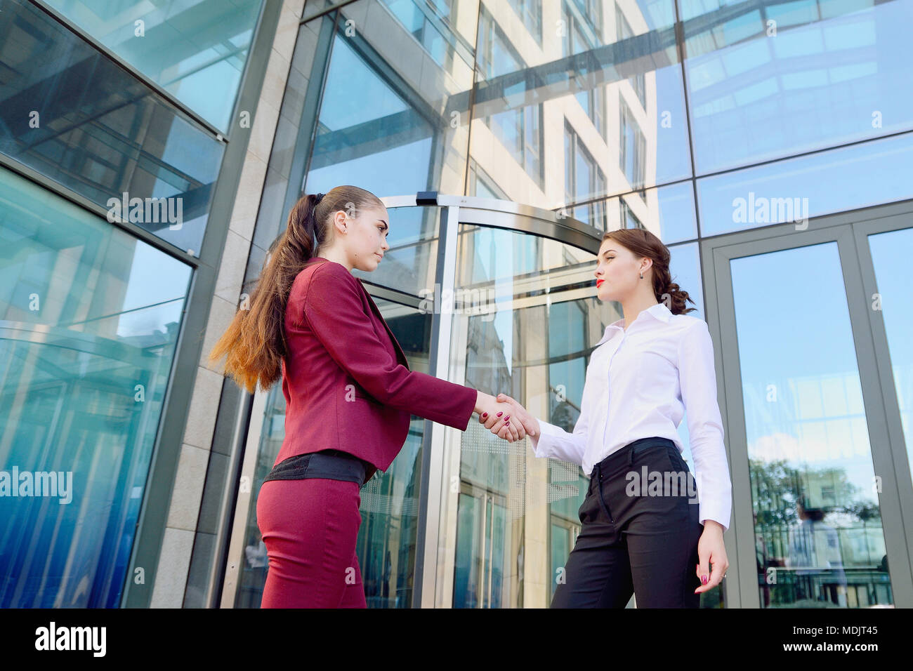 Handshake of two young girls against the background of a multi-storey ...
