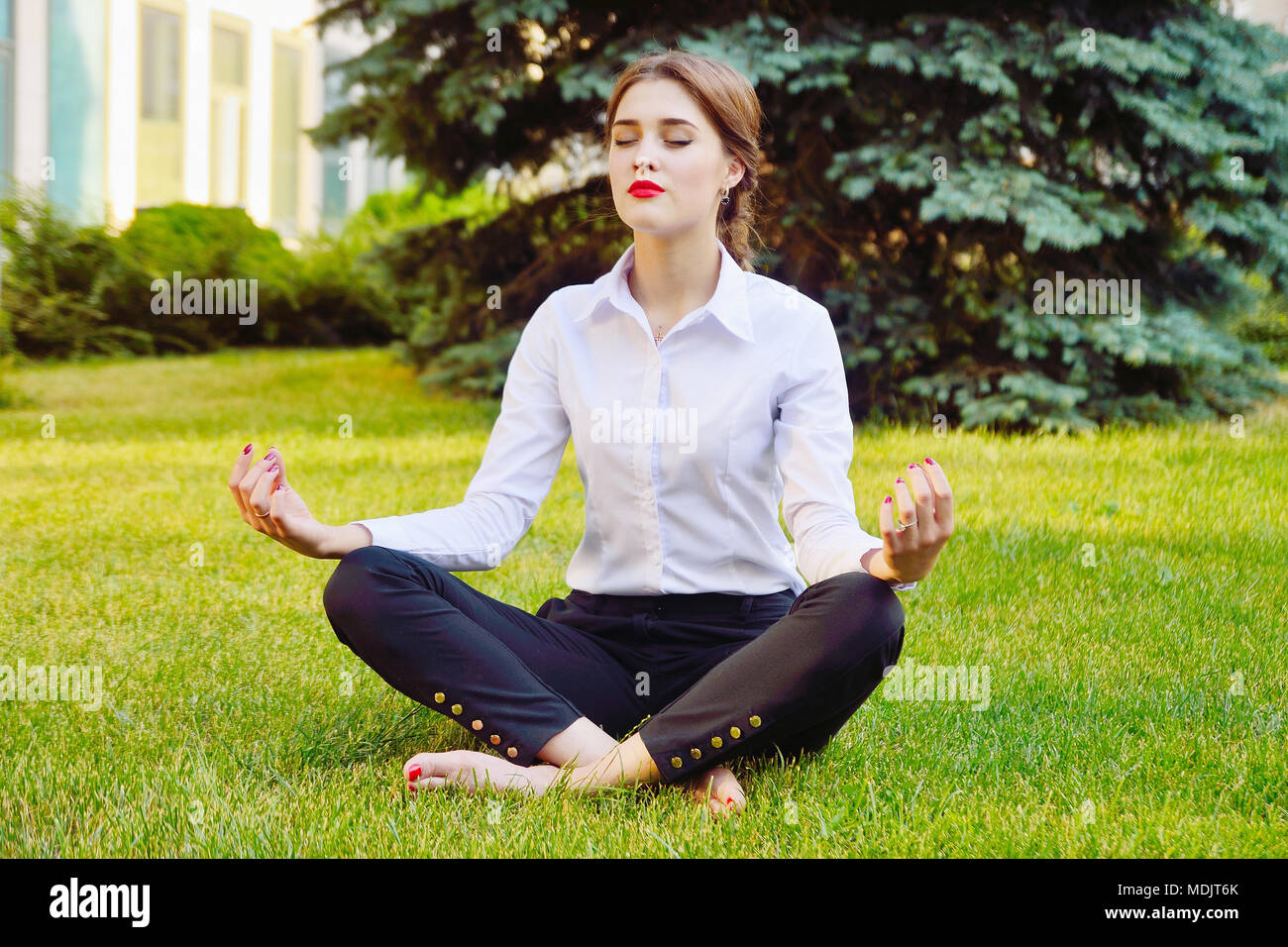Office yoga. Business lady in lotus pose sits on green grass ...