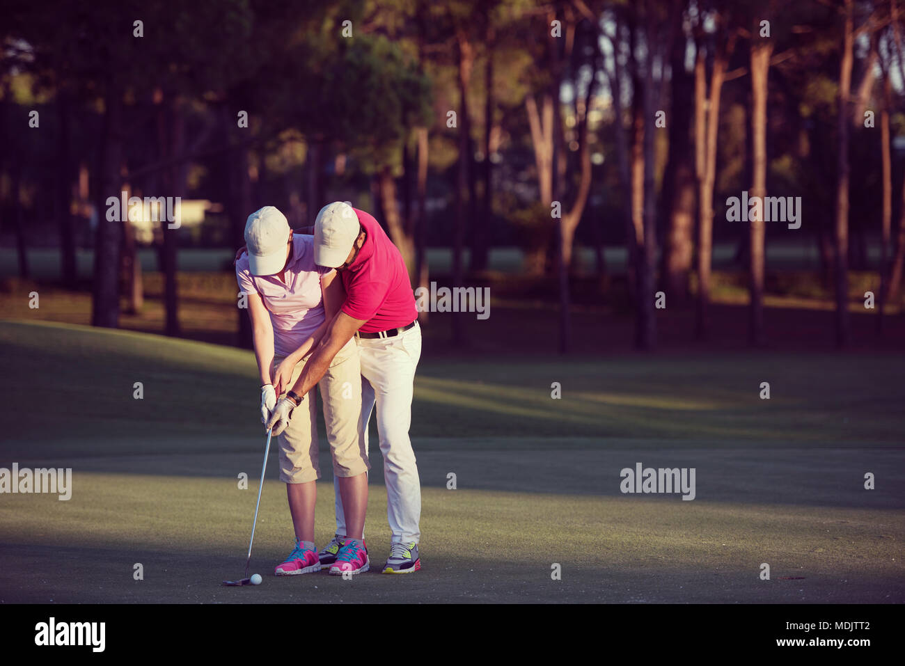 male golf instructor teaching female golf player, personal trainer ...