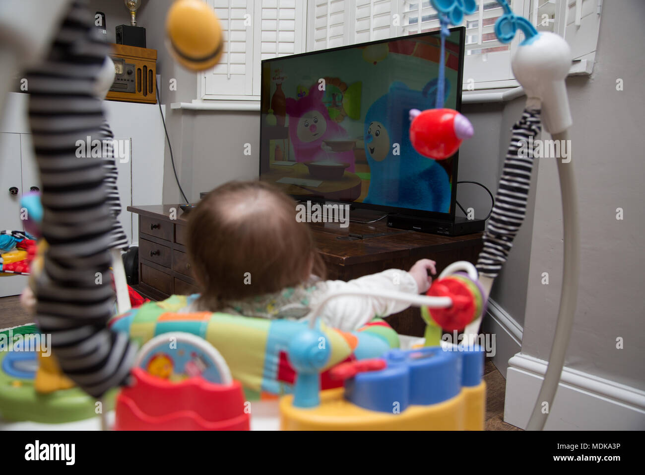 Baby in jumperoo watching television Stock Photo - Alamy