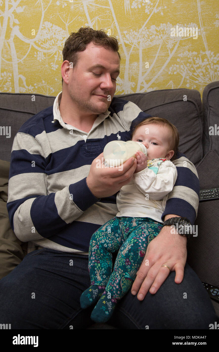 Exhausted dad bottle feeding baby Stock Photo - Alamy