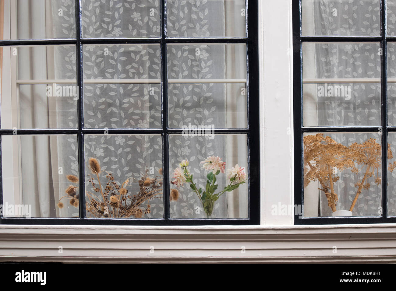Traditional Dutch window with tulle and dry bouquets on the windowsill ...