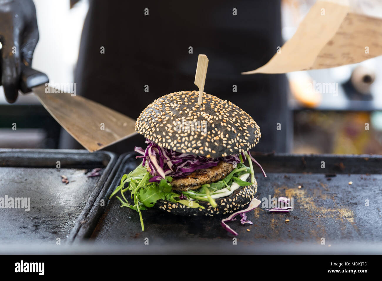 Chef preparing burgers at grill plate on international urban street ...