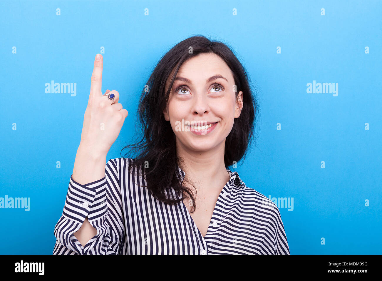 Smiling young woman pointing up Stock Photo - Alamy