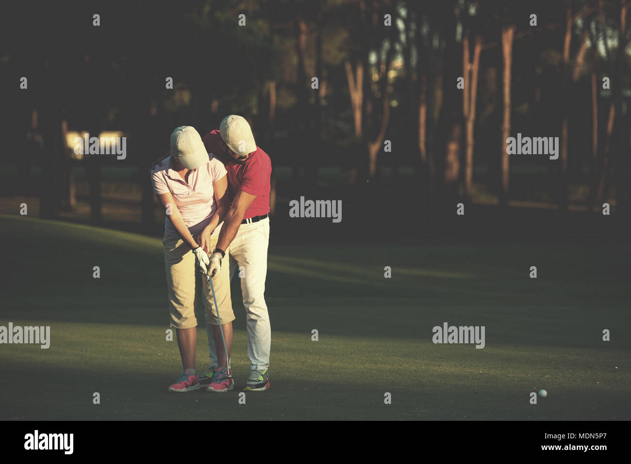 male golf instructor teaching female golf player, personal trainer ...