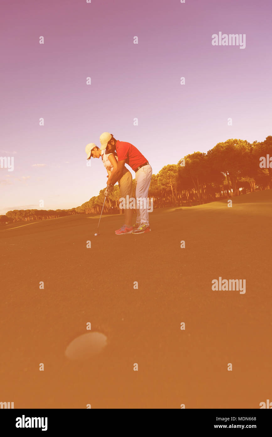 male golf instructor teaching female golf player, personal trainer ...