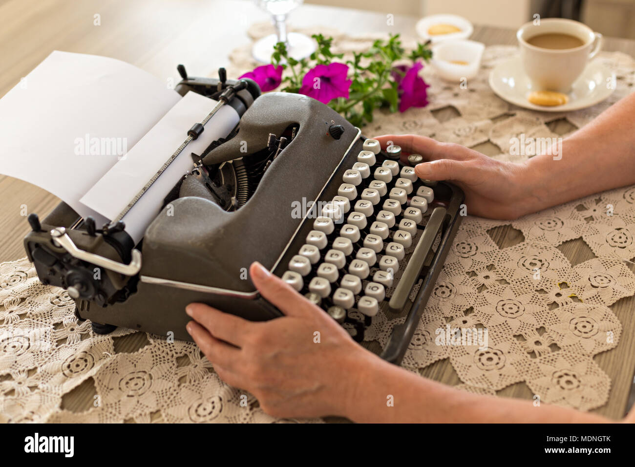Writing workplace. Female hands holding retro typewriter placed on lace ...